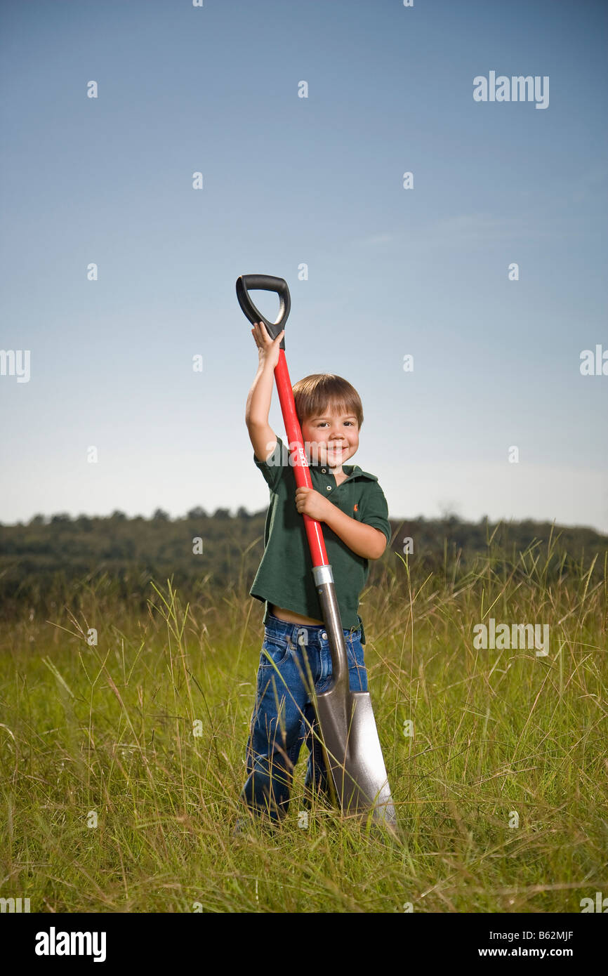 Cute little boy holding a shovel in a grass field about to dig Stock ...