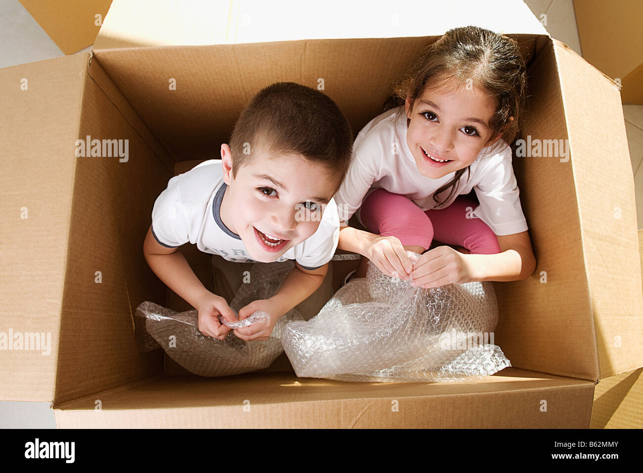 Portrait of two children sitting in a cardboard box and smiling Stock ...