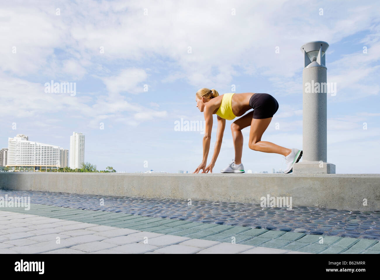 Side profile of a mid adult woman in a running position on the ledge ...