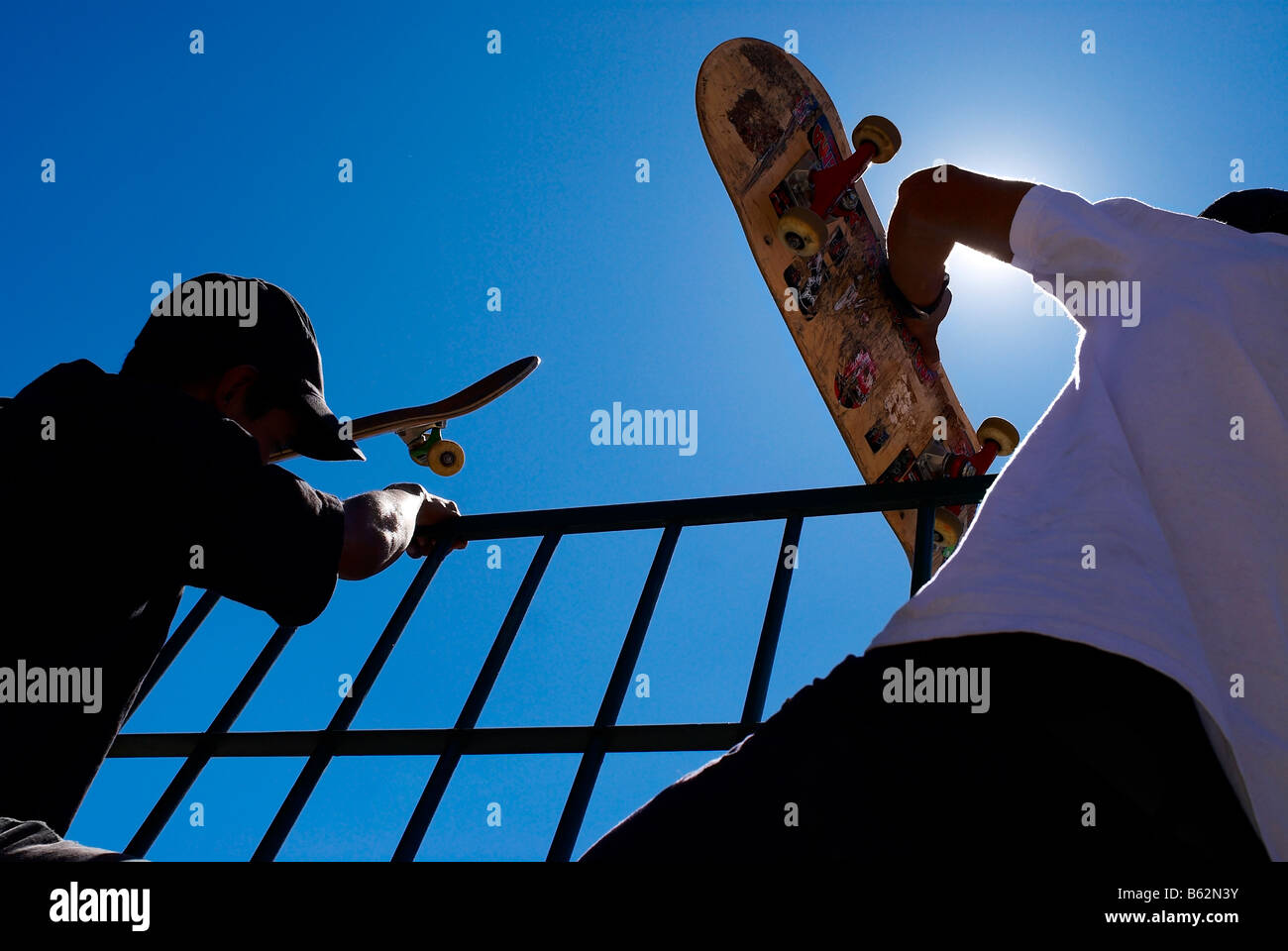 Low angle view of a young man and a mid adult man climbing a railing ...