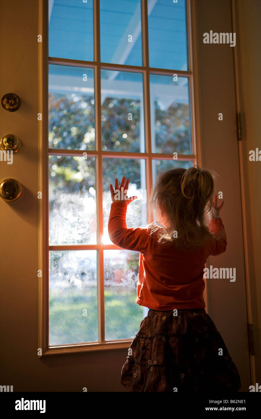Rear view of a girl looking through a door Stock Photo - Alamy