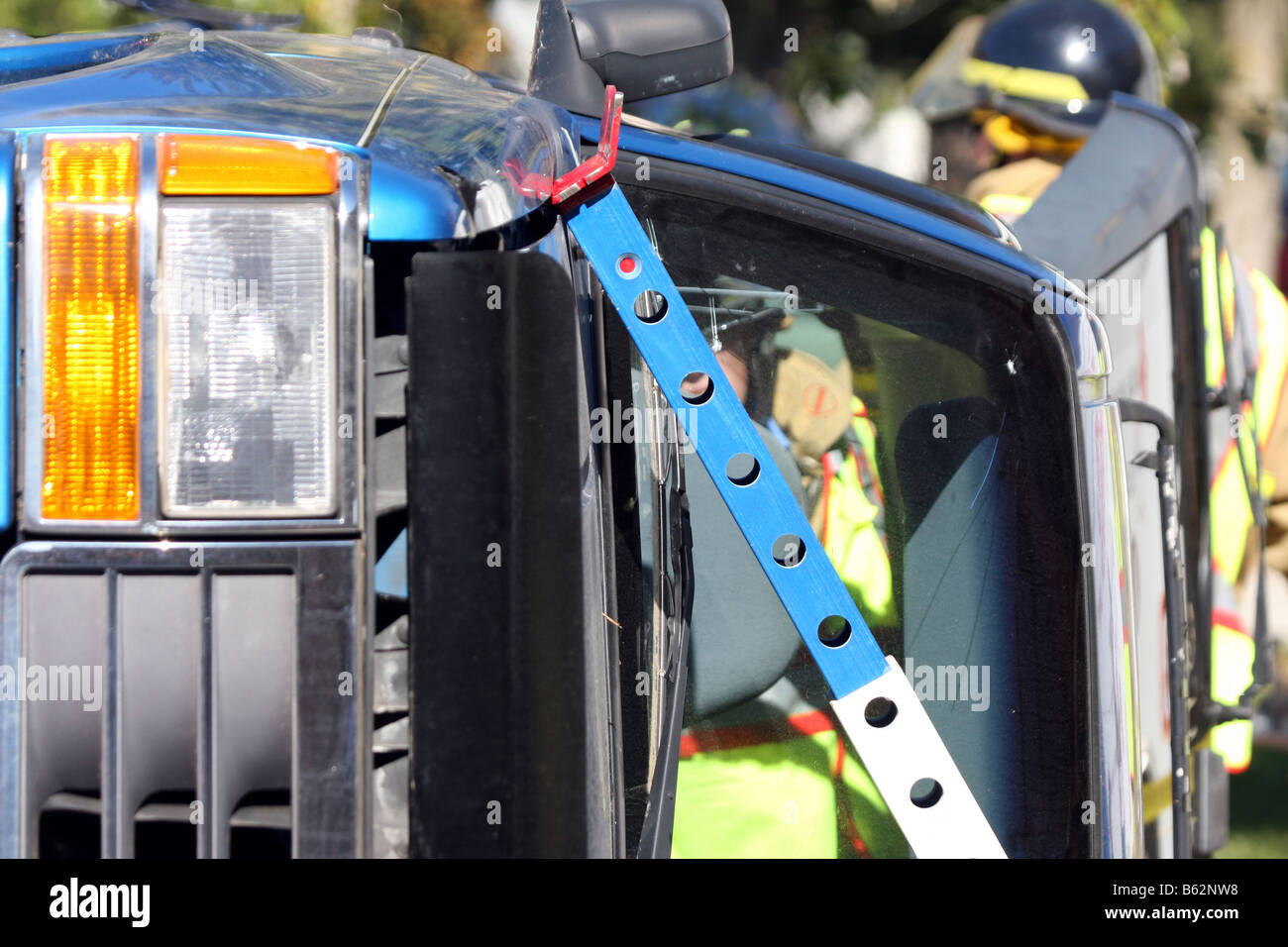 Firefighters working on stabilizing a car that has rolled over by using ...