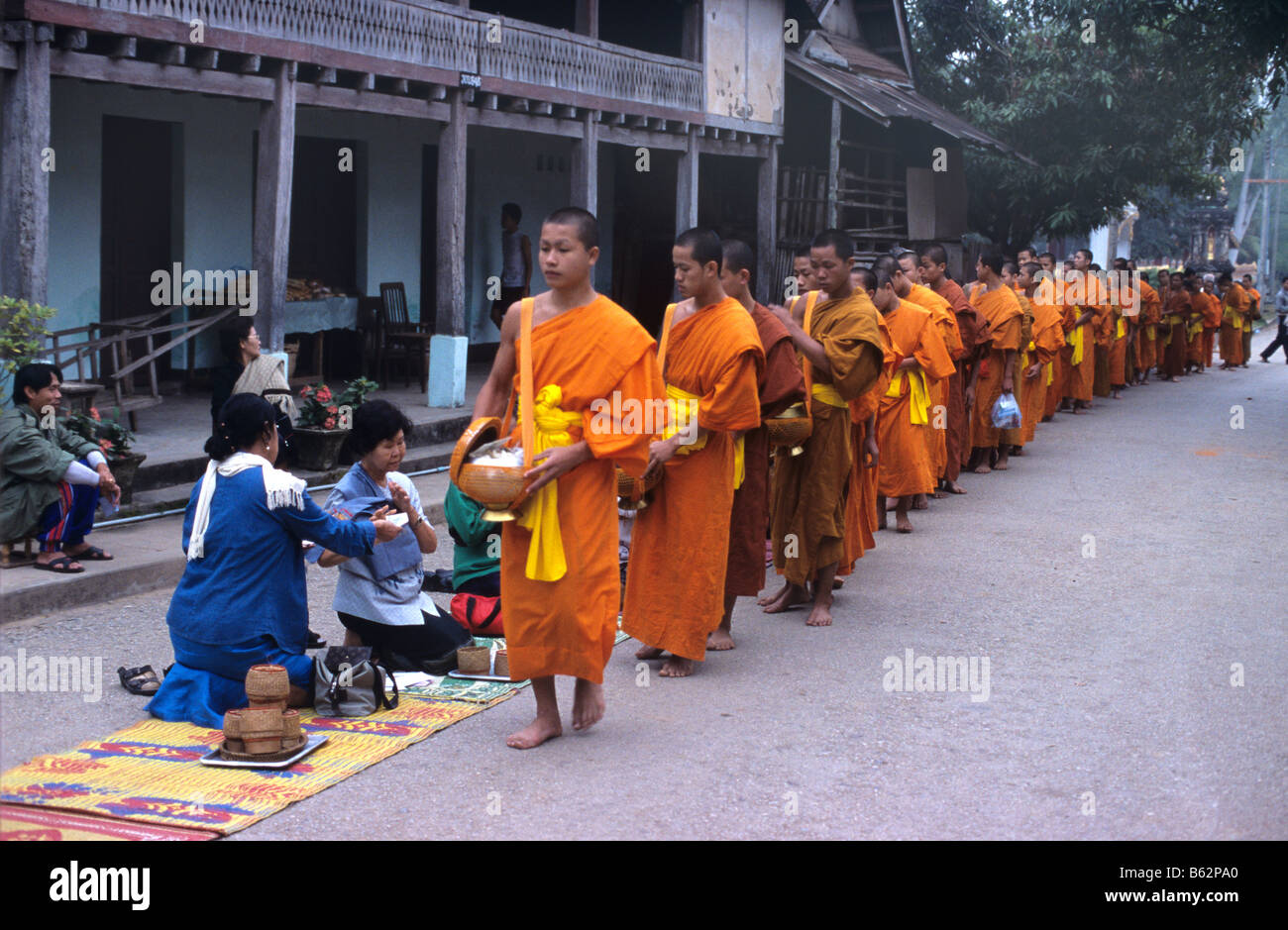 Saffron-robed Buddhist monks receive alms at dawn at Luang Prabang, the ...