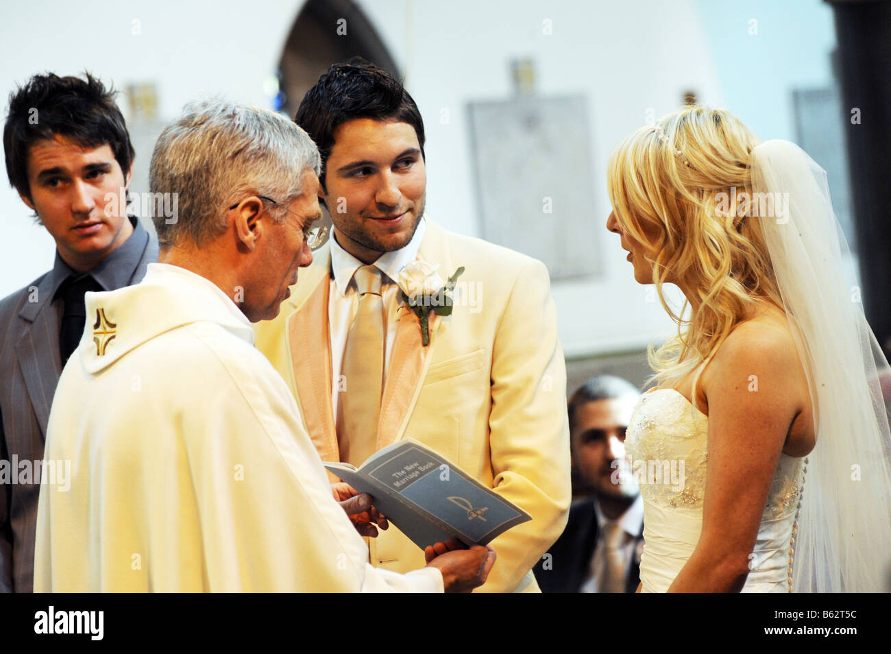 A bride and groom exhange rings at the church altar while exchanging ...