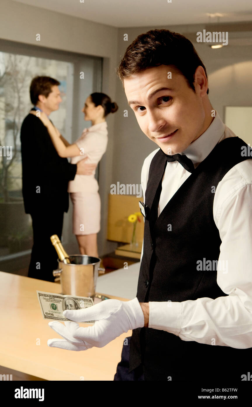Portrait of a waiter holding US paper currency and smiling Stock Photo ...