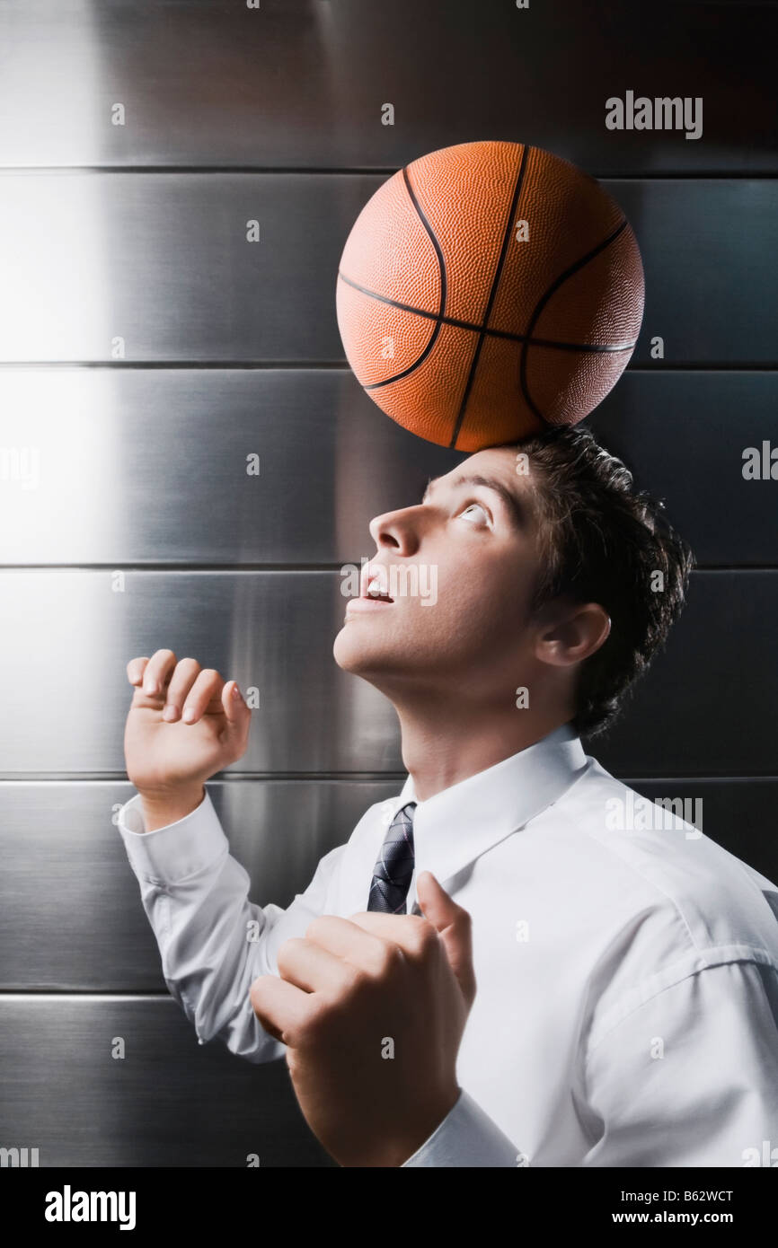 Side profile of a businessman balancing a basketball on his forehead ...