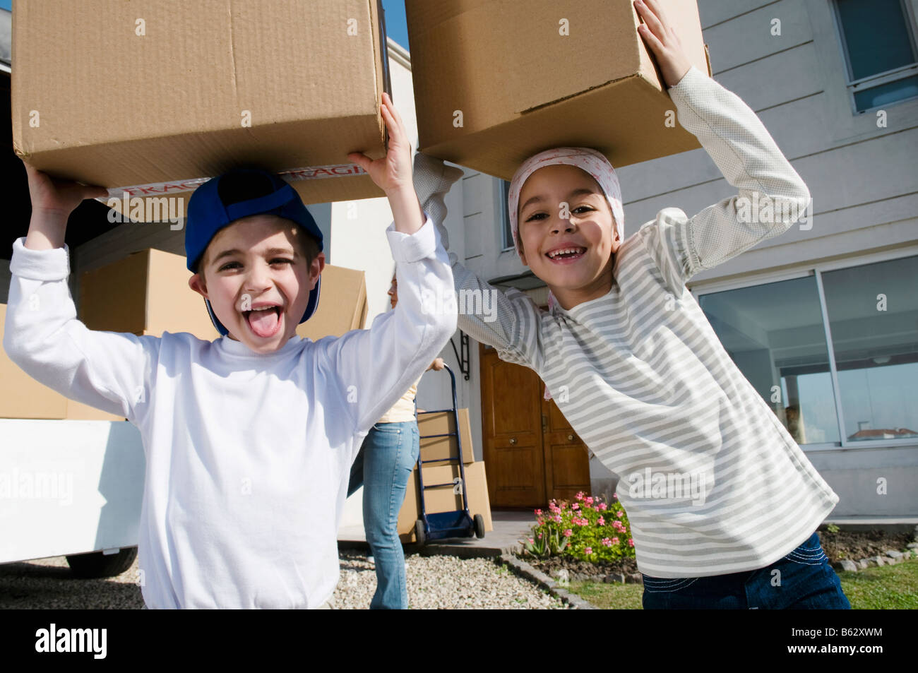 Portrait of a boy and a girl carrying cardboard boxes Stock Photo - Alamy