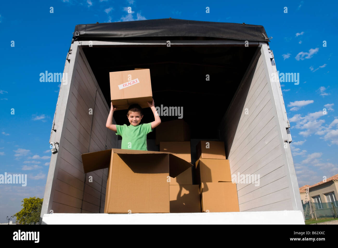 Portrait of a boy carrying a cardboard box and smiling Stock Photo - Alamy