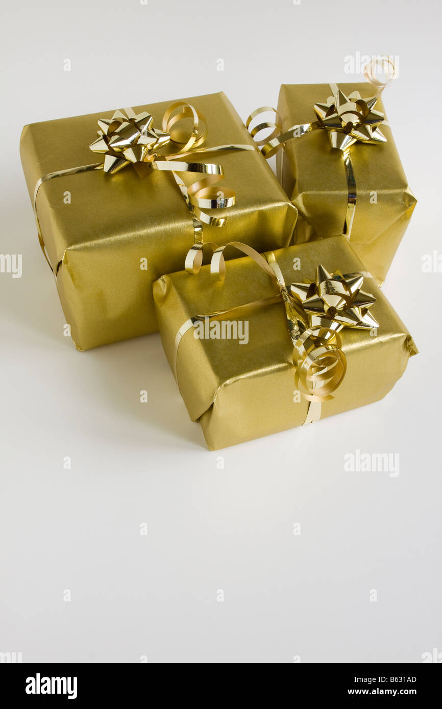 A group of three parcels gift wrapped in gold paper Stock Photo - Alamy
