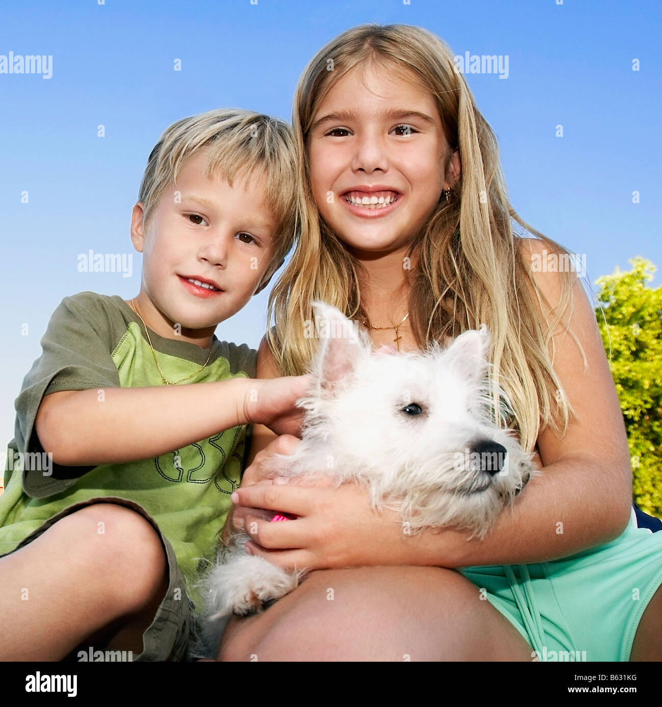 Portrait of two children carrying a dog and smiling Stock Photo - Alamy