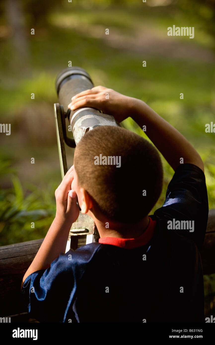 Rear view of a boy looking through a hand-held telescope Stock Photo ...