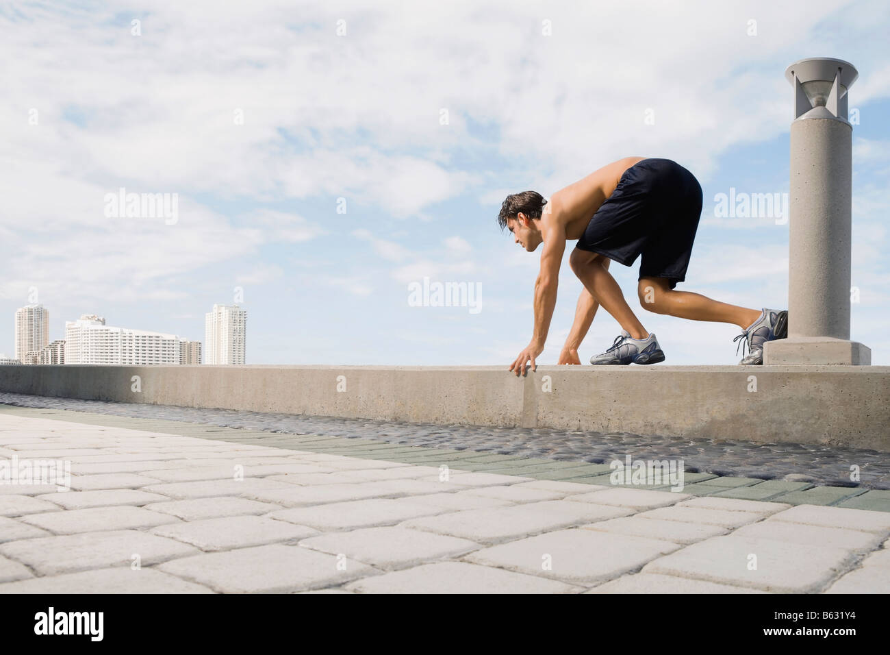 Side profile of a young man in running position on the ledge Stock ...