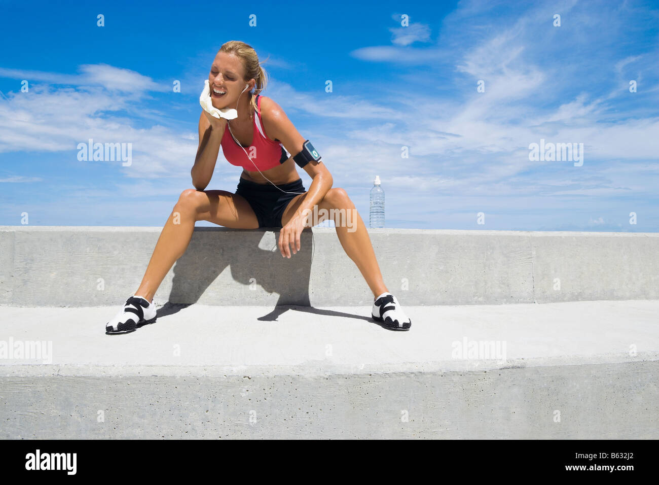 Mid adult woman sitting on a ledge Stock Photo - Alamy