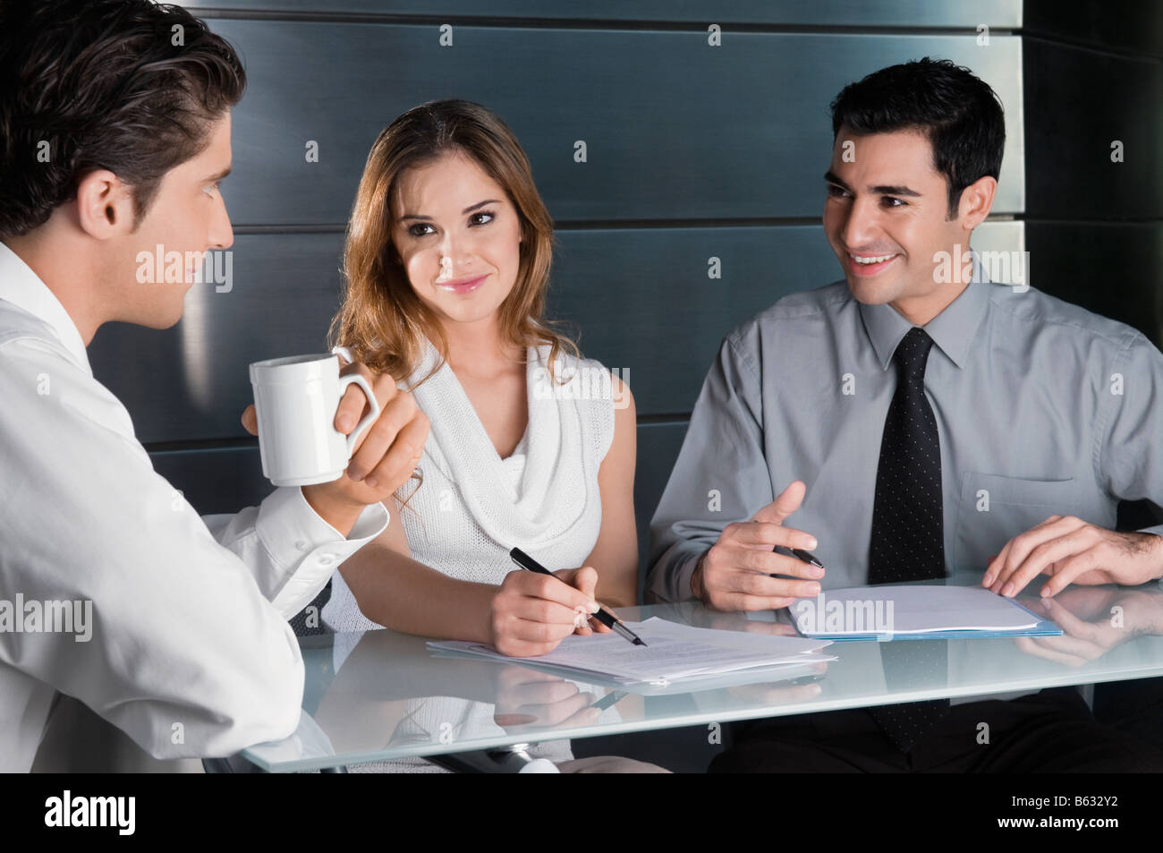 Two businessmen and a businesswoman talking in an office Stock Photo ...