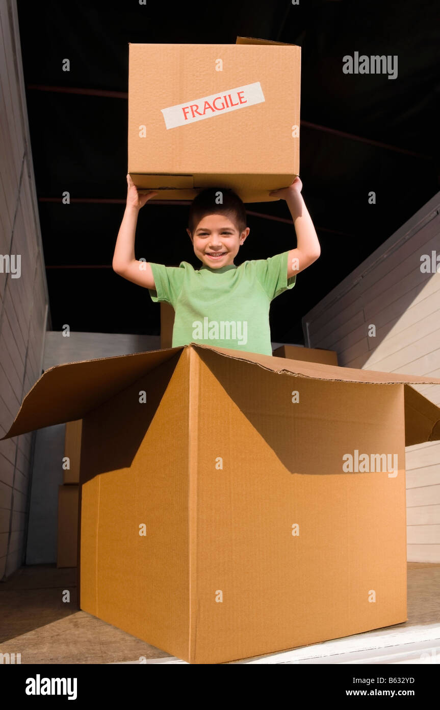 Portrait of a boy carrying a cardboard box and smiling Stock Photo - Alamy