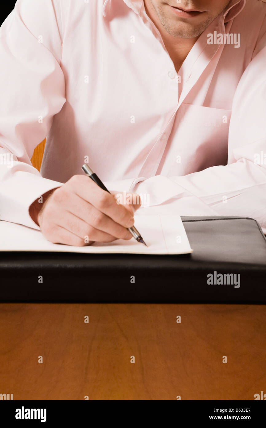 Businessman writing on a sheet of paper with a pen Stock Photo - Alamy
