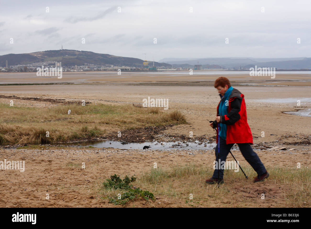 Middleaged Woman walking on Blackpill Beach, Swansea Bay, with Swansea ...