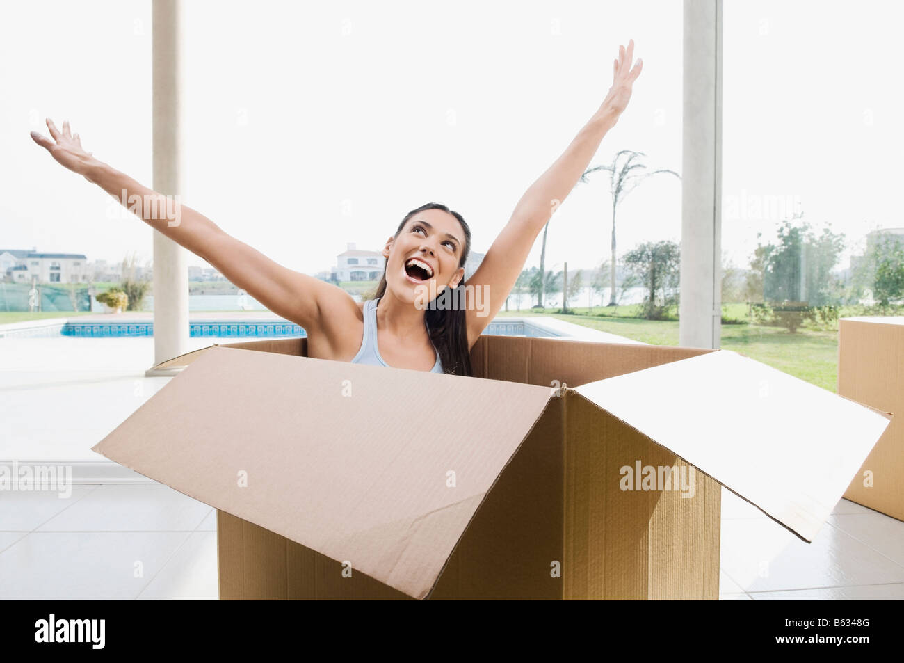 Young woman sitting in a cardboard box and laughing Stock Photo - Alamy