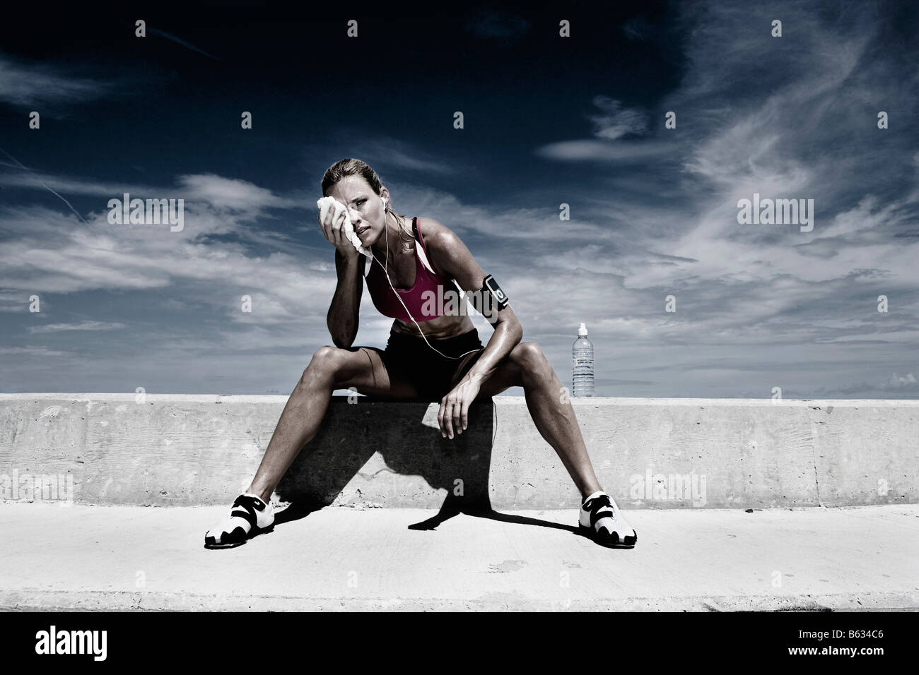 Mid adult woman sitting on a ledge Stock Photo - Alamy