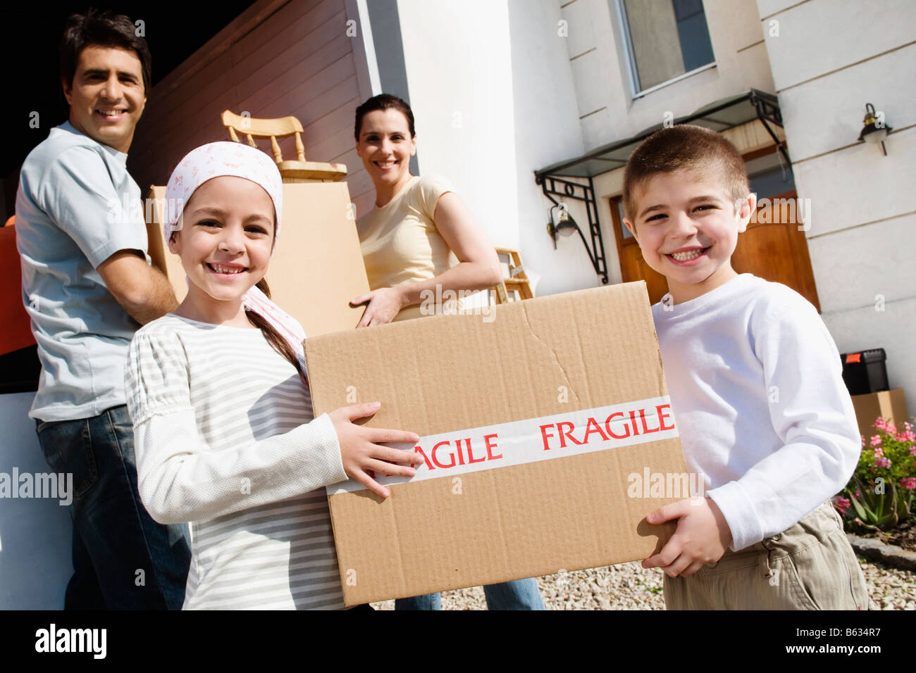 Portrait of a family carrying cardboard boxes and smiling Stock Photo ...
