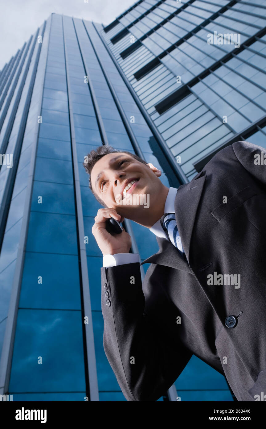 Low angle view of a businessman talking on a mobile phone and smiling ...