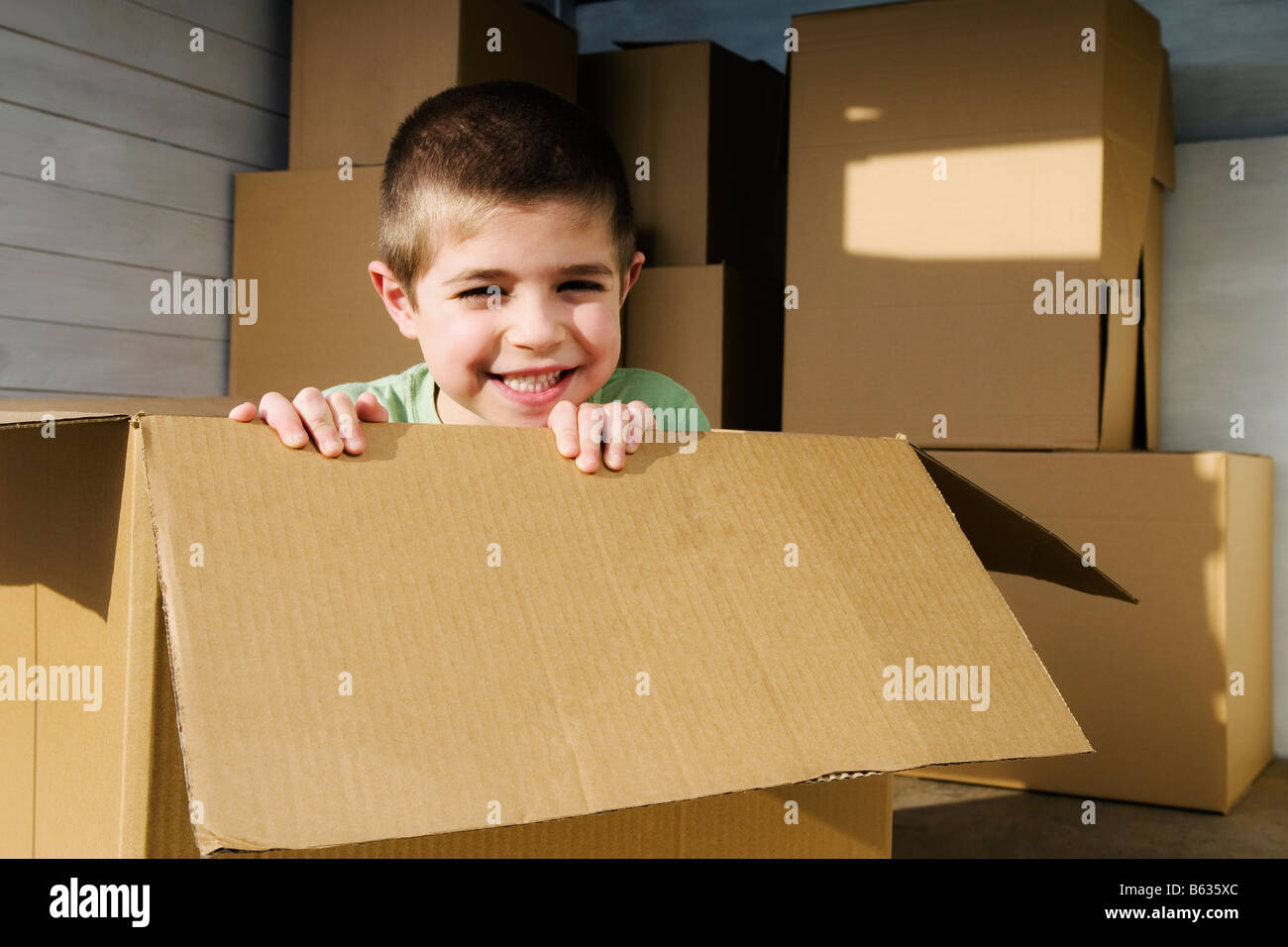 Portrait of a boy sitting in a cardboard box and smiling Stock Photo ...