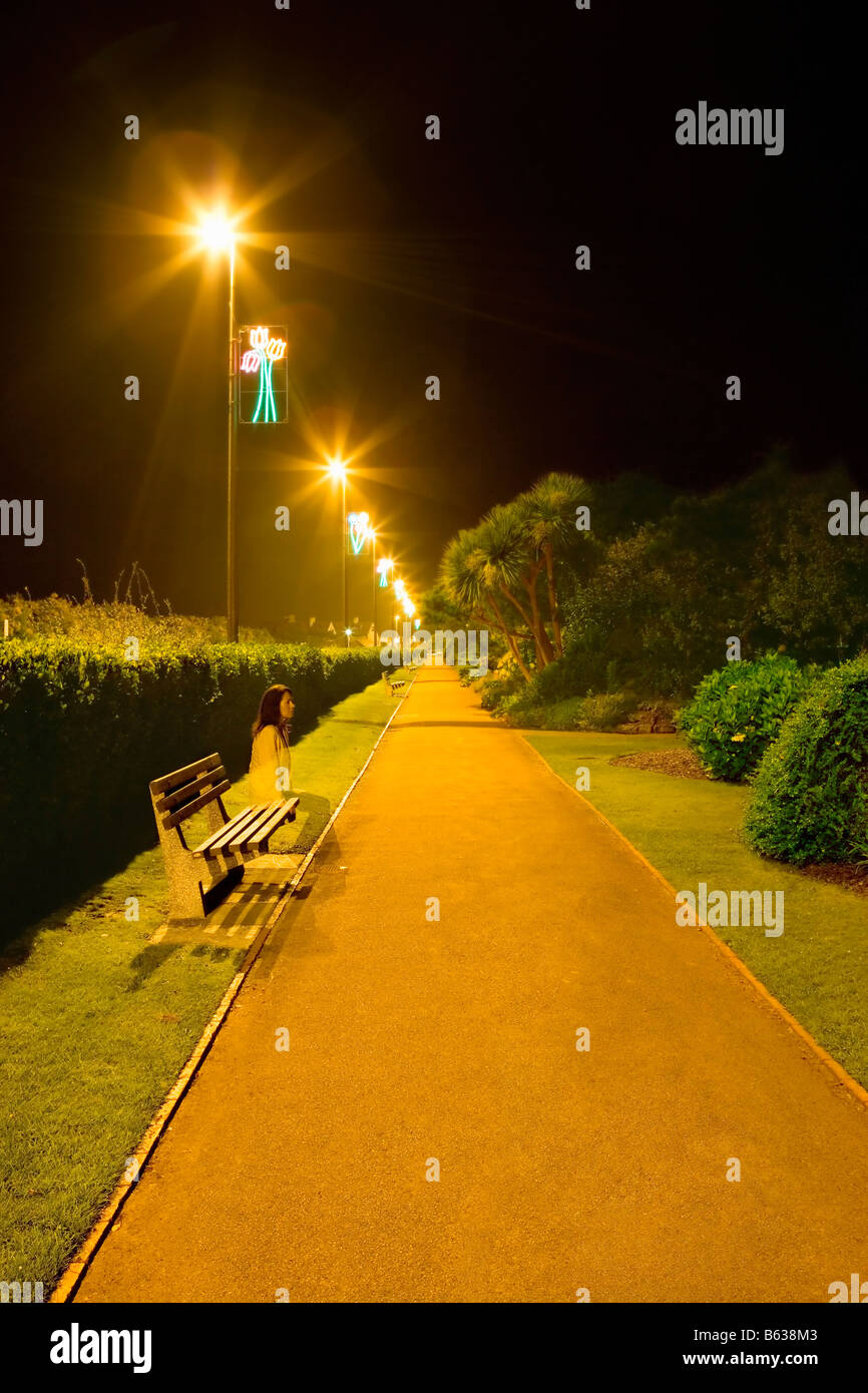 Woman sitting on park bench at night Stock Photo - Alamy
