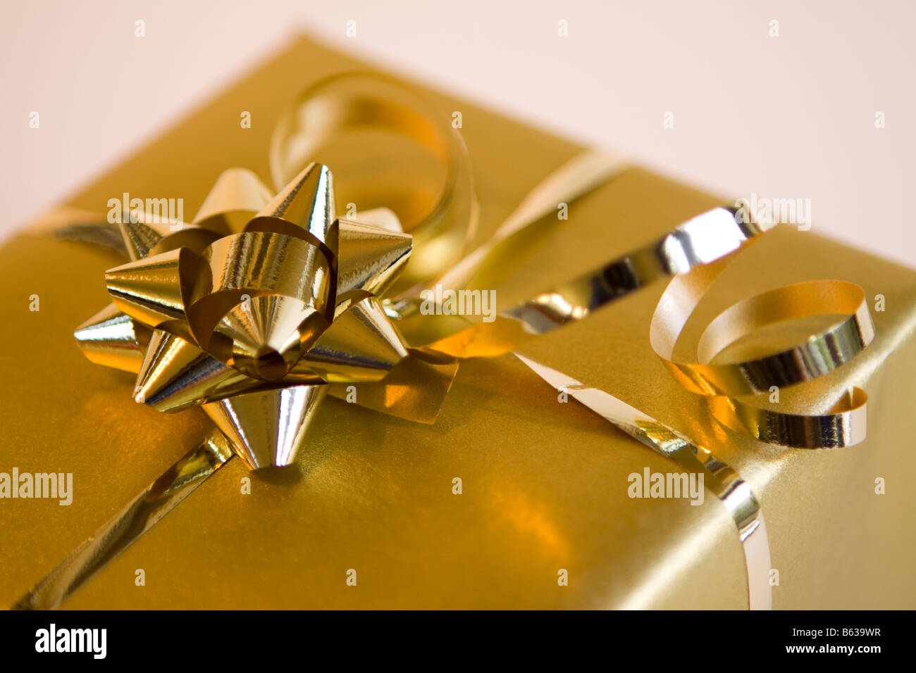 A close up of a parcel wrapped in gold paper with a bow Stock Photo - Alamy