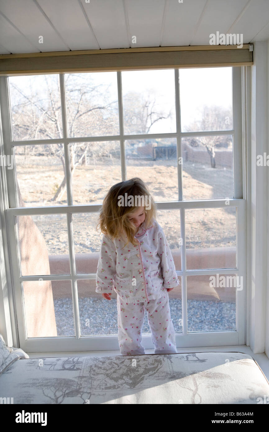 Baby girl standing in front of a window Stock Photo - Alamy