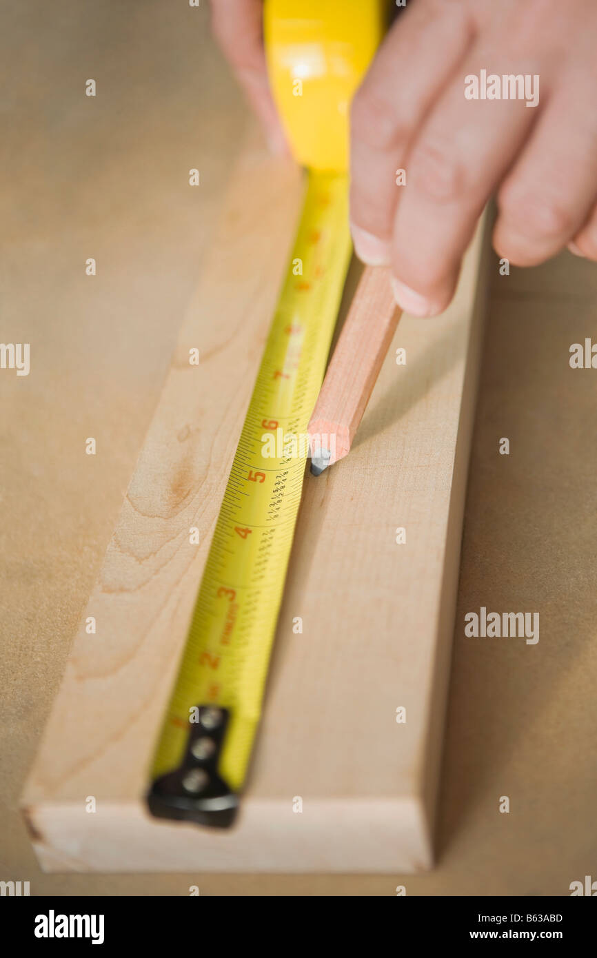 Close-up of a person's hands measuring a wooden plank Stock Photo - Alamy