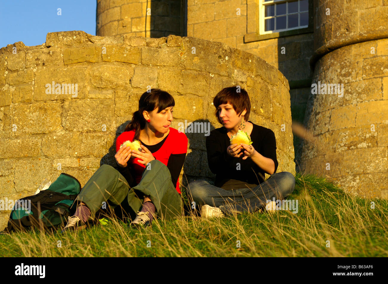 Two hungry girls eating sandwiches outdoor. Broadway Tower ...