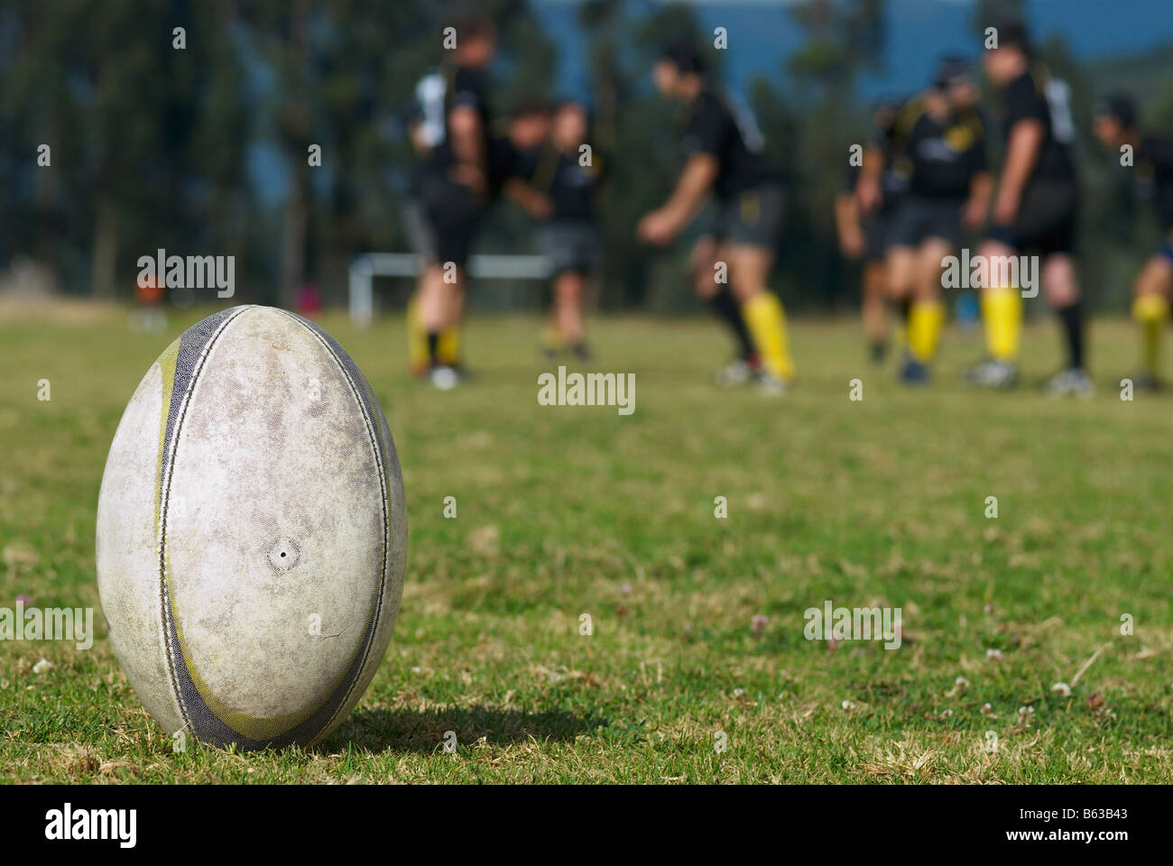Close-up of a rugby ball in a field with rugby players in the ...