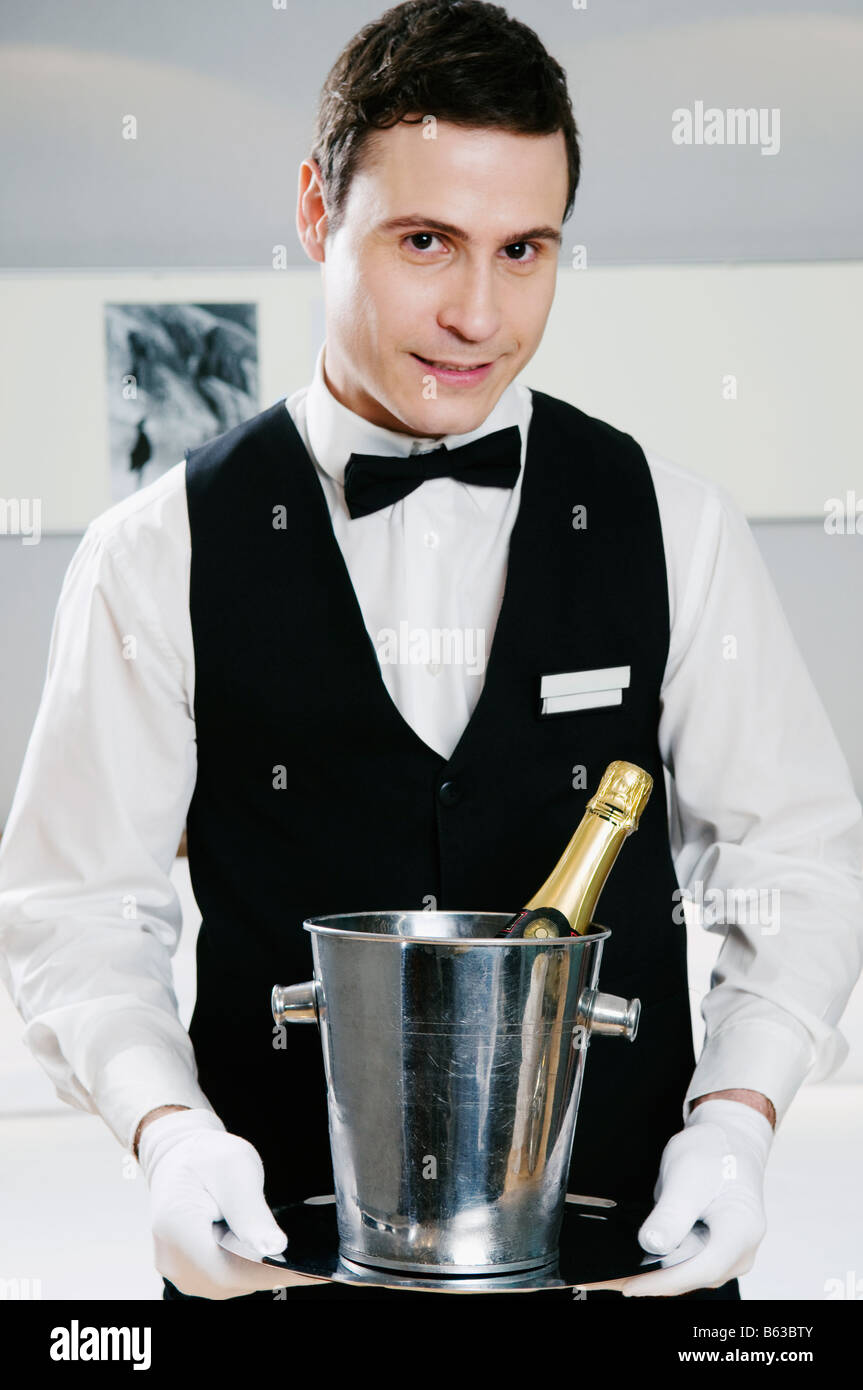 Portrait of a waiter holding a champagne bottle in an ice bucket Stock ...