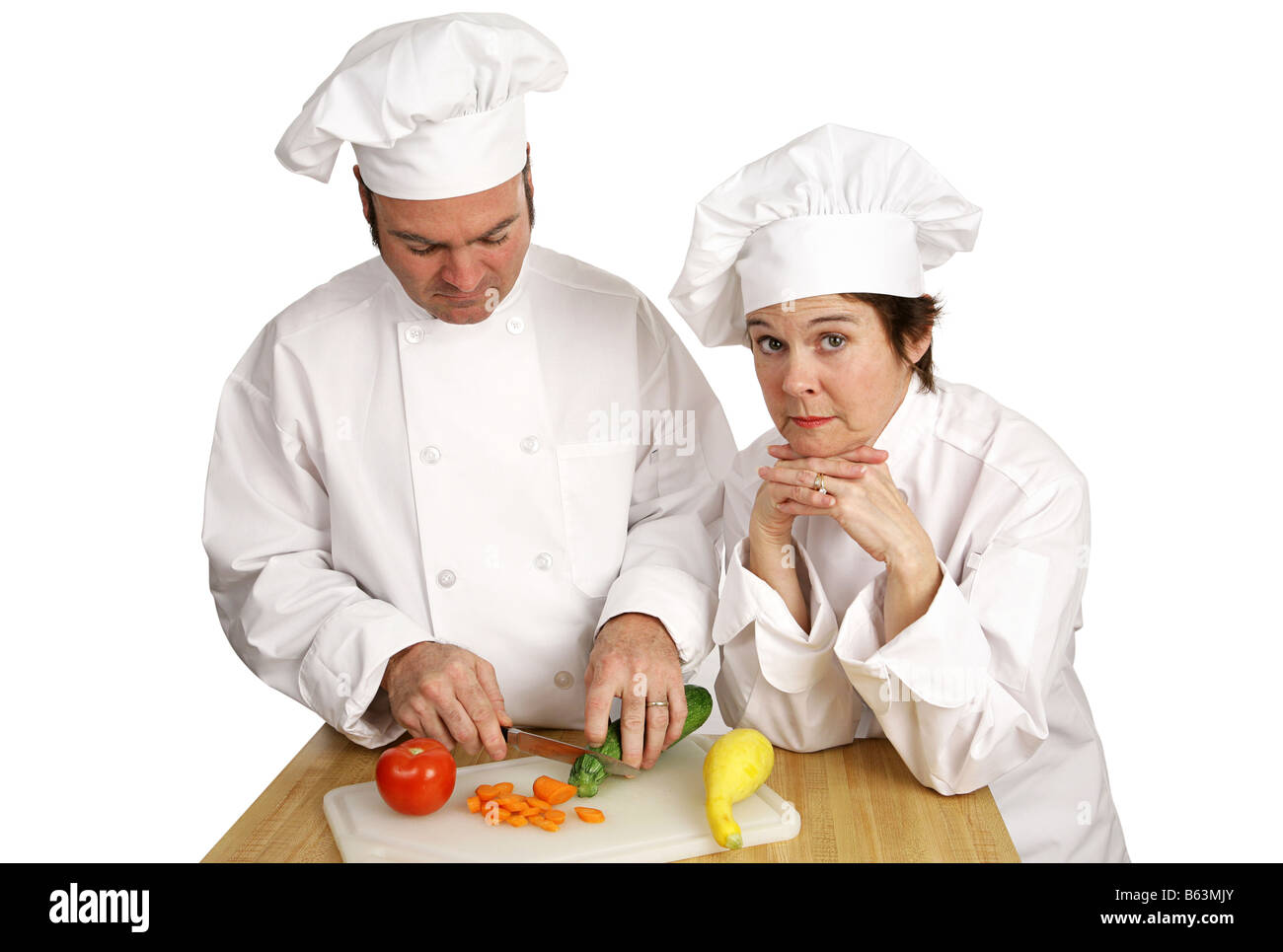 A student chef preparing food while a stern instructor looks on ...