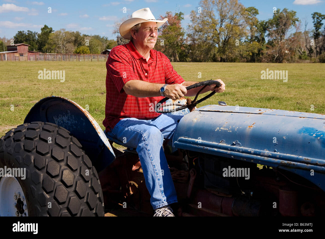 Handsome mature cowboy riding his tractor through his fields Stock ...