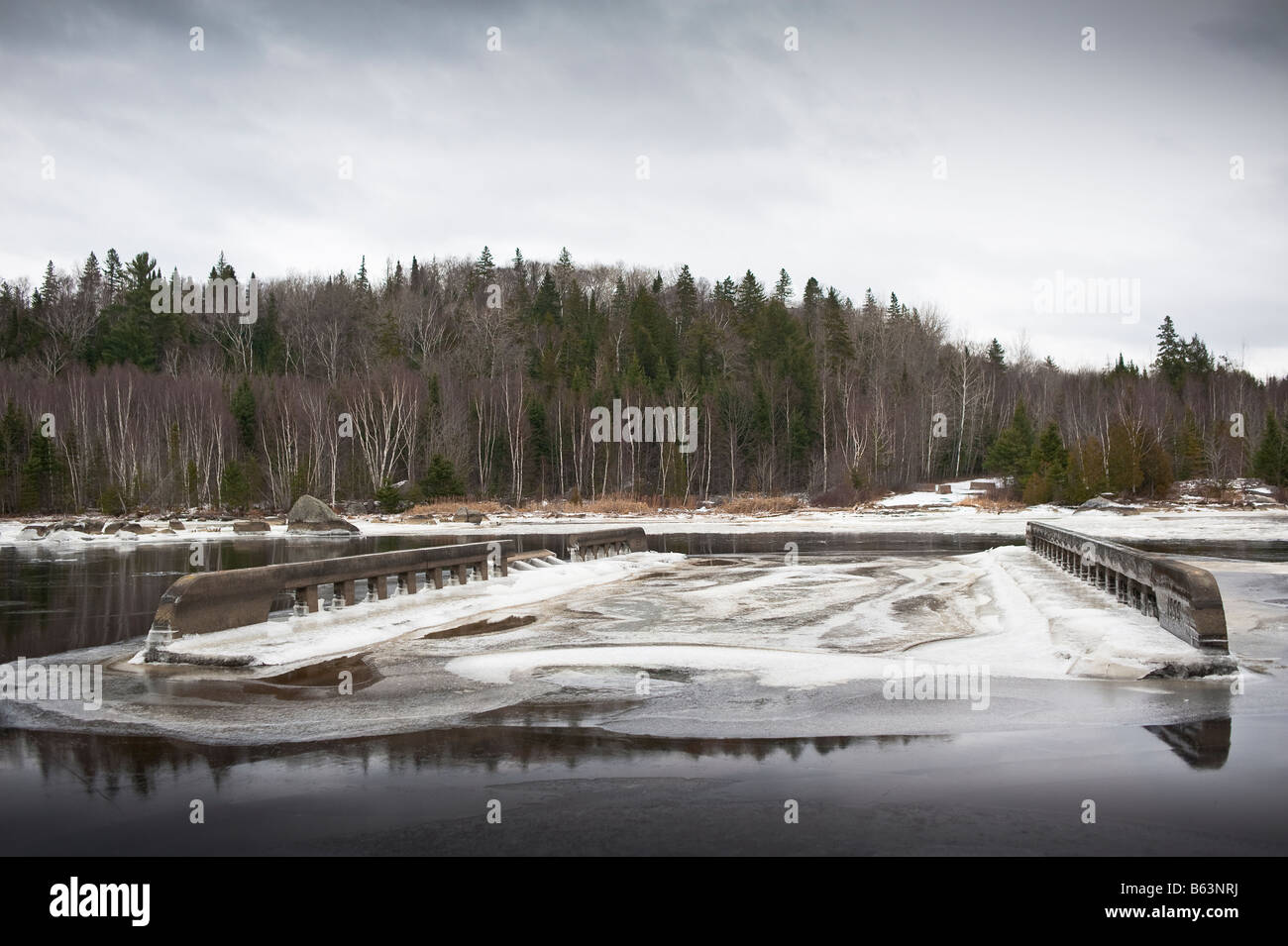 washed out road and bridge from flooding with ice forming on water in ...