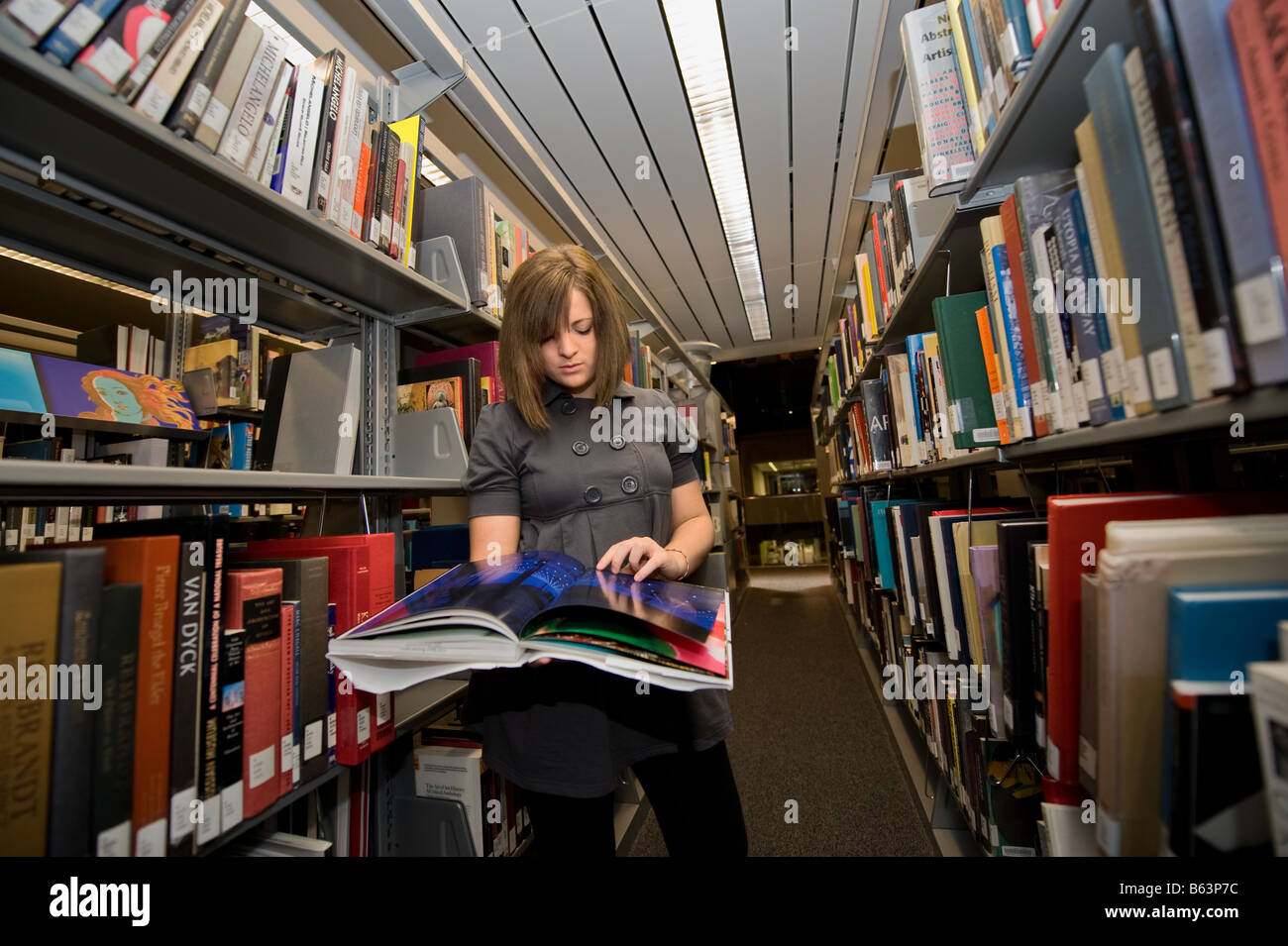 Young woman looking at a book in a school library Stock Photo - Alamy