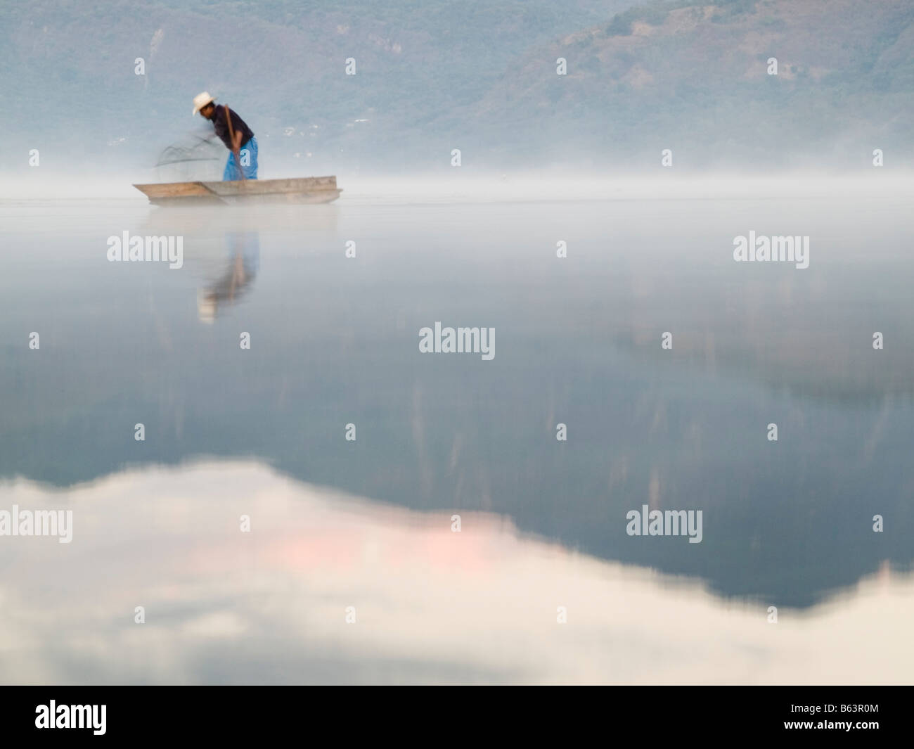 A fishermen and reflection on the surface of lake Stock Photo - Alamy