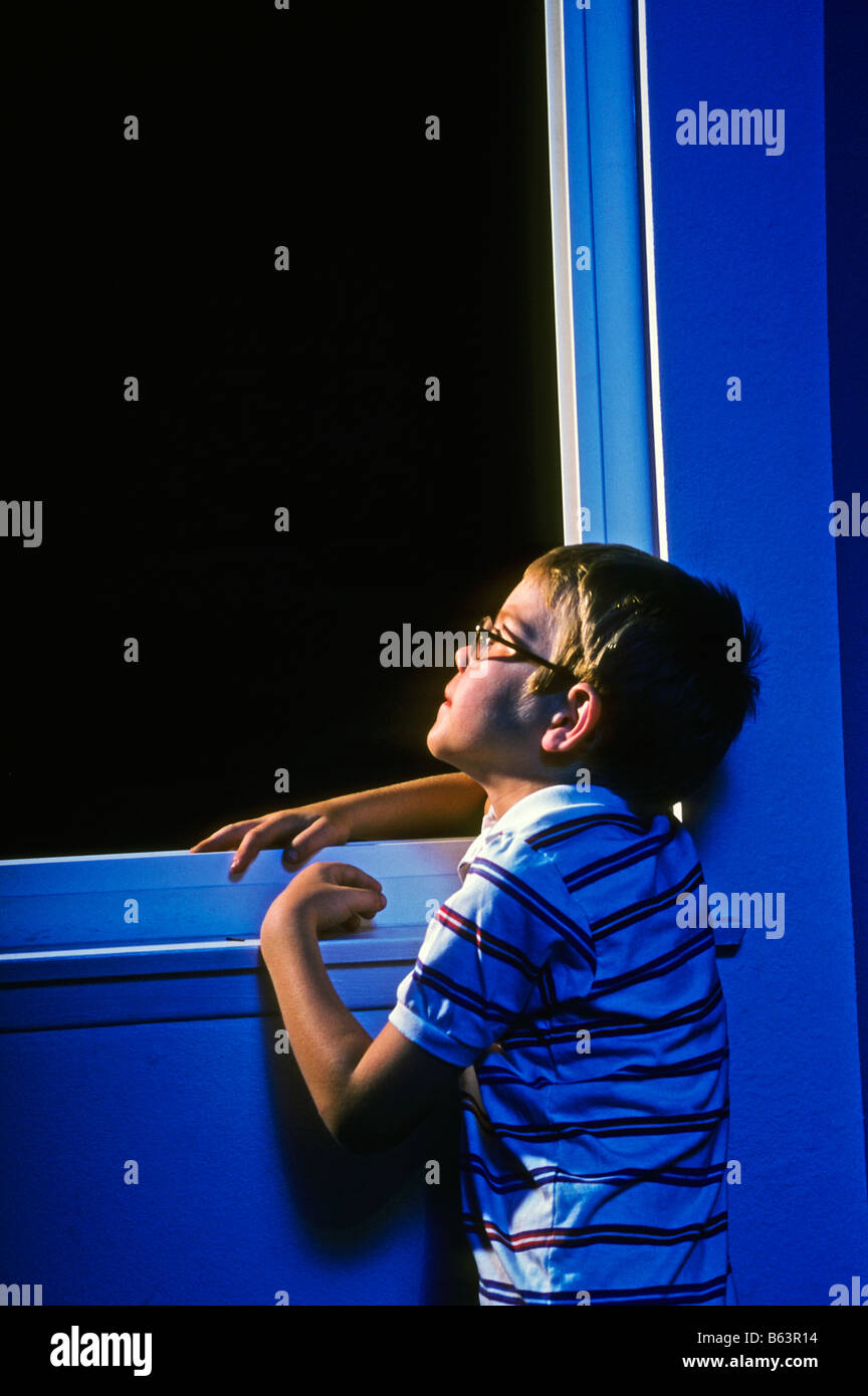 Young boy looks out window at night Stock Photo - Alamy