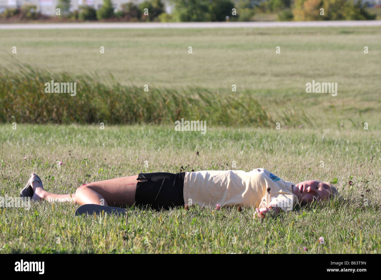 A teenage girl in shorts is injured and laying on her back in a field ...