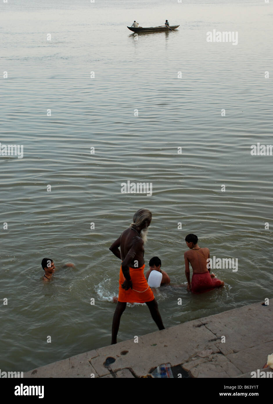 Holy man walking by the river Ganges and boys playing in the water ...