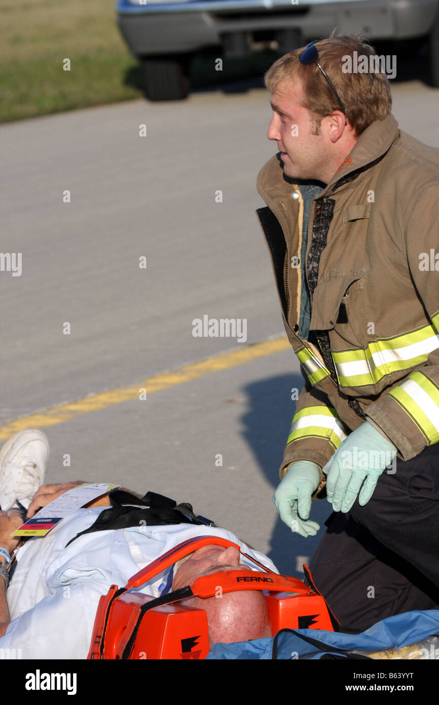 An EMT leaning over and helping a patient on a backboard and head ...