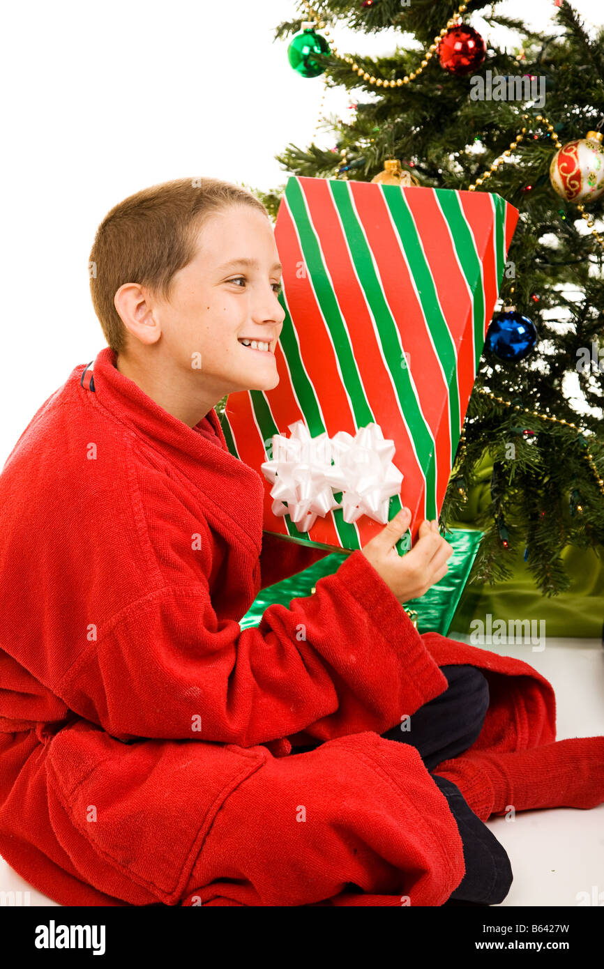 Adorable little boy shaking a Christmas gift trying to guess whats ...