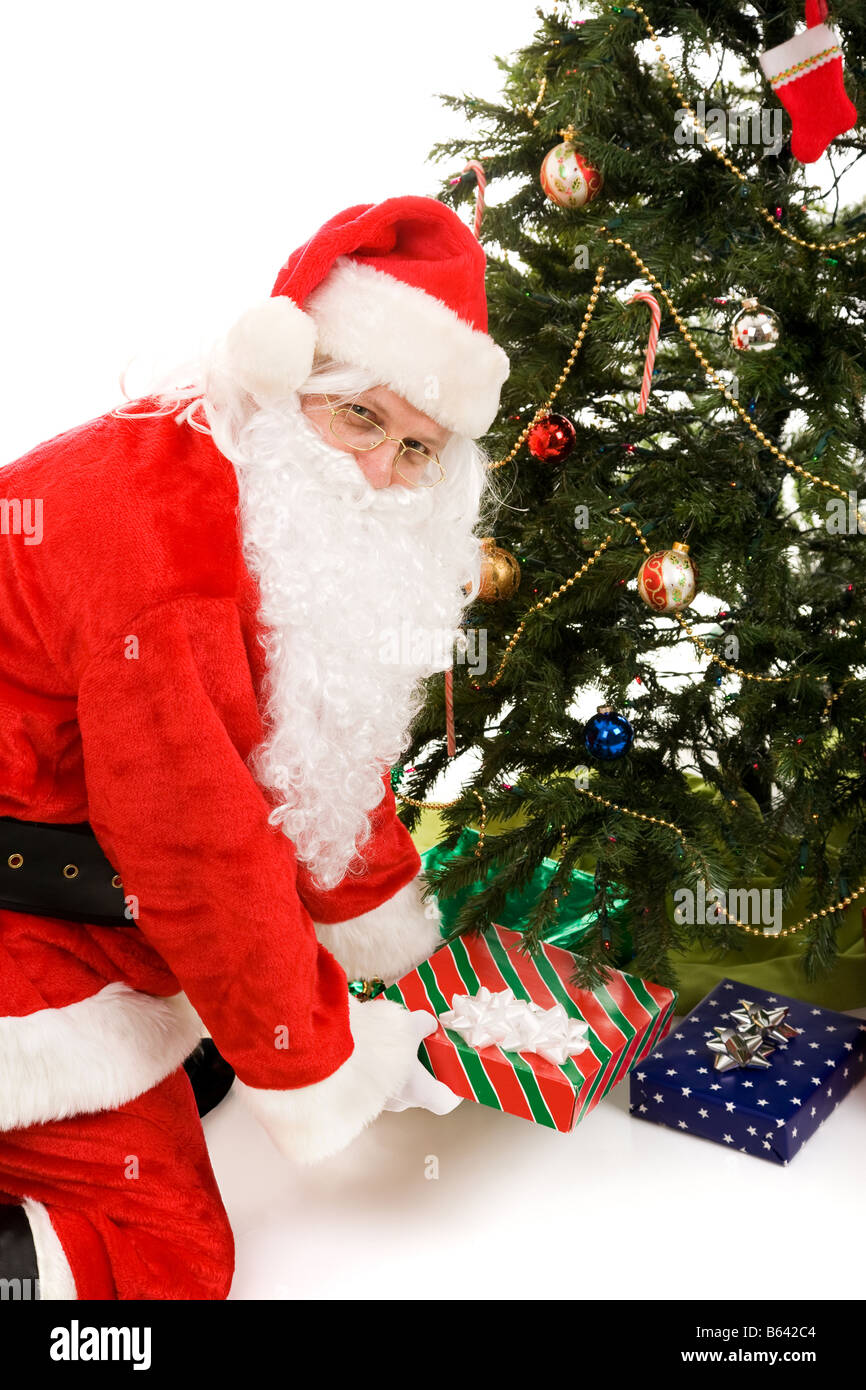 Santa putting Christmas presents under the tree Isolated on white Stock ...