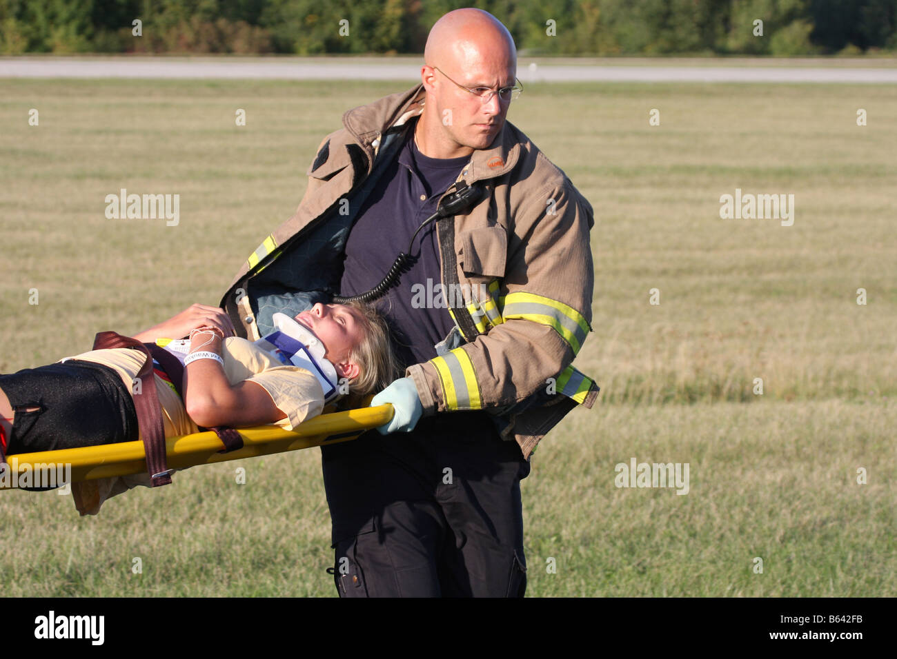 An EMS personnel carrying an injured women on a backboard to a cot at a ...