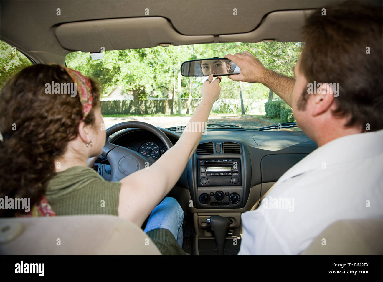Teen girl and her driving instructor adjusting rearview mirror Focus on ...