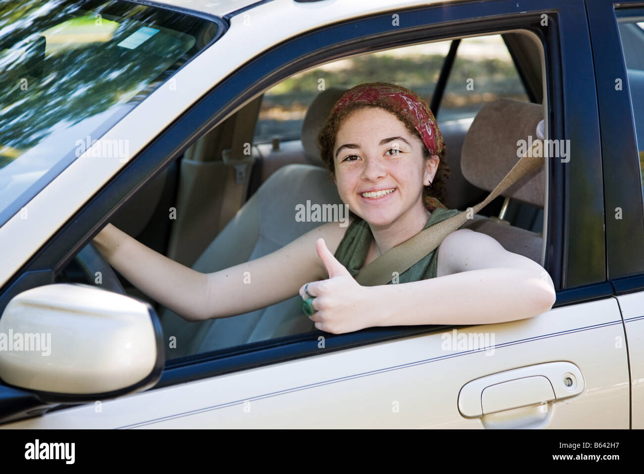 Cute teen driver giving the thumbs up after passing her driving test ...