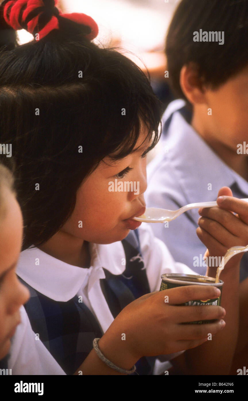 Young Asian-American girl eats pudding during school lunch break Stock ...