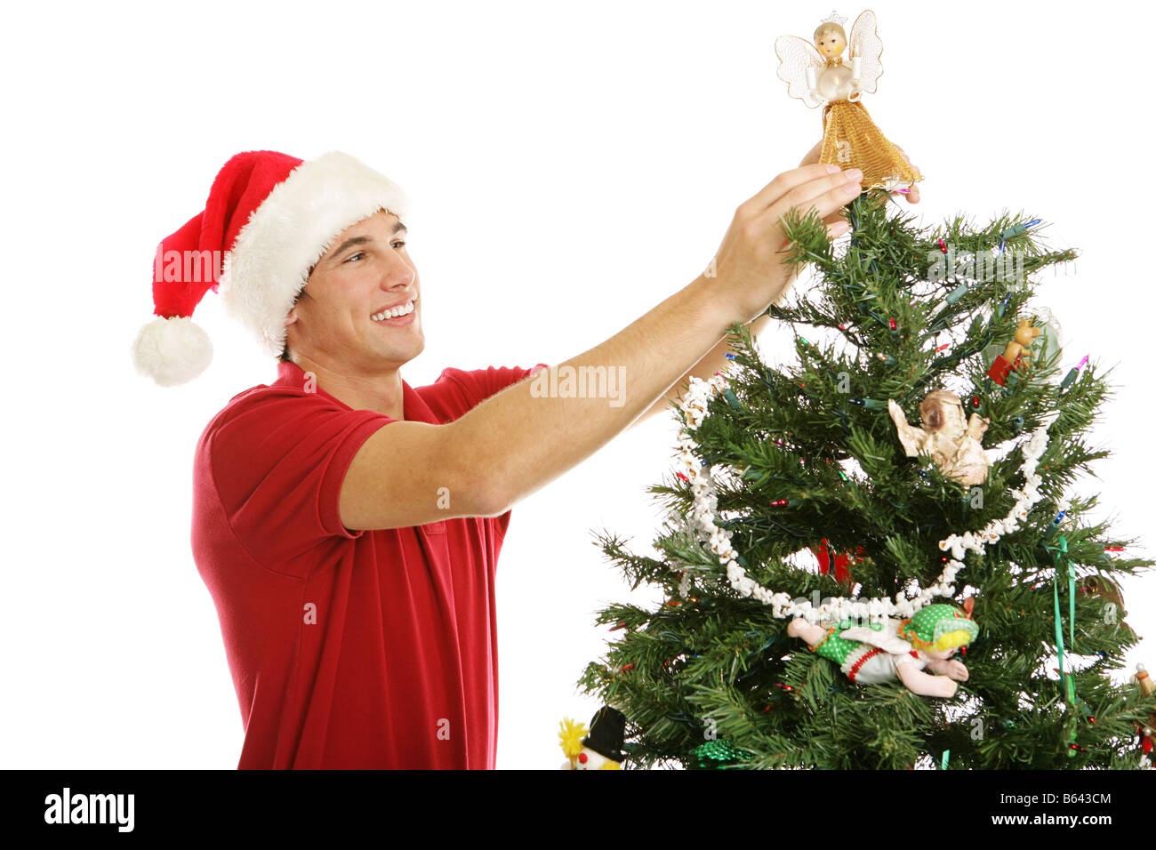 Tall handsome young man placing the angel on the top of the tree ...