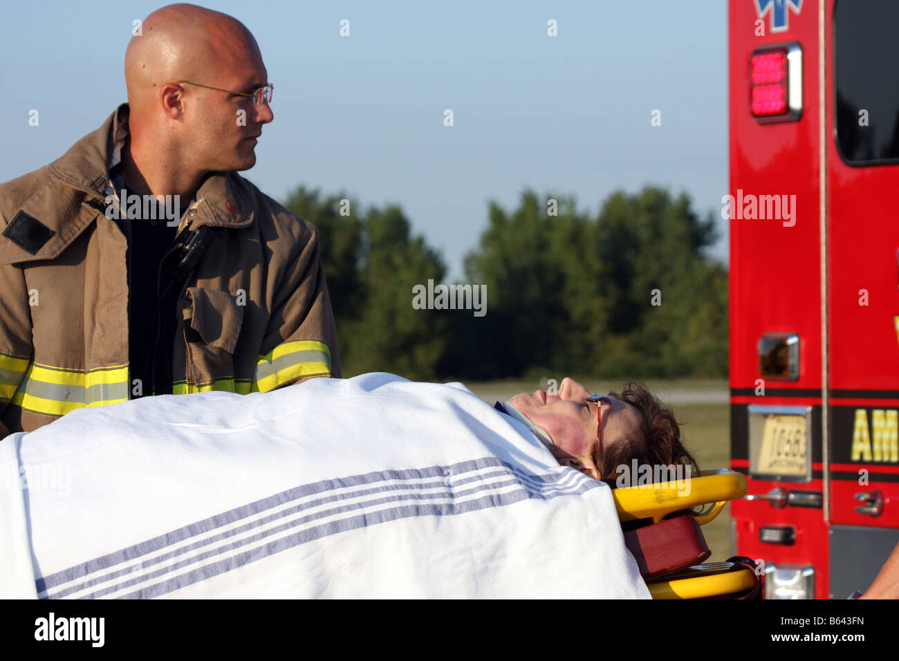 A paramedic placing a female patient on a cot into the ambulance Stock ...